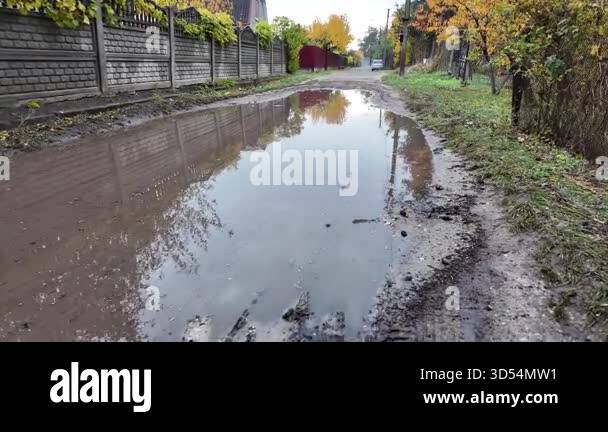 Puddles on the road, slow motion. Autumn raindrops fall into a large ...