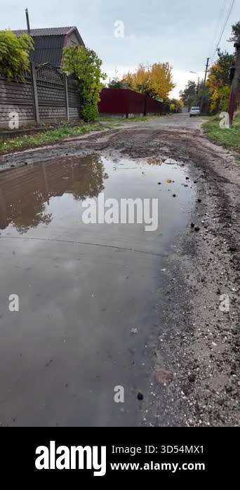 Puddles on the road, slow motion. Autumn raindrops fall into a large ...