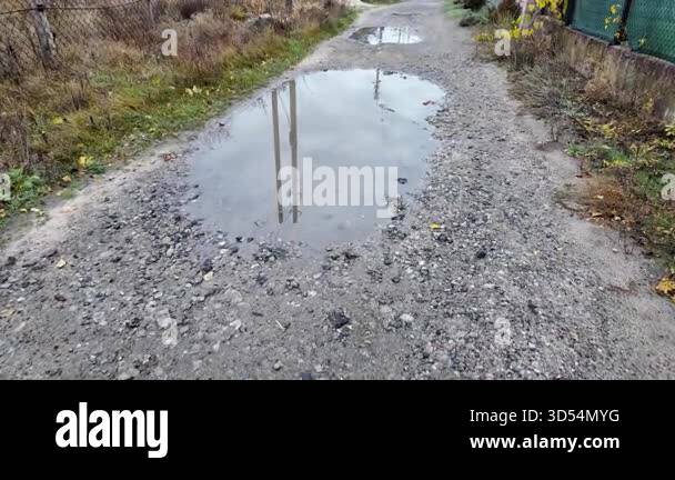 Puddles on the road, slow motion. Autumn raindrops fall into a large ...