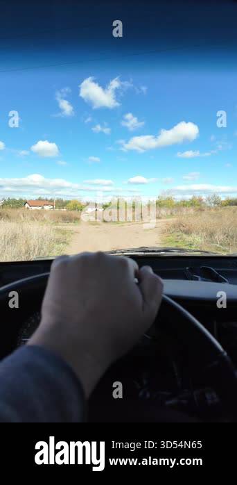 Drivers perspective from inside a car on a sunny day, hand on steering ...