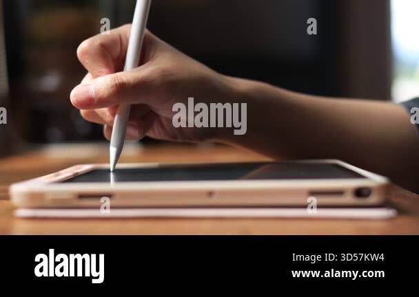 Horizontal footage of woman's hand using stylus pen to draw on tablet ...