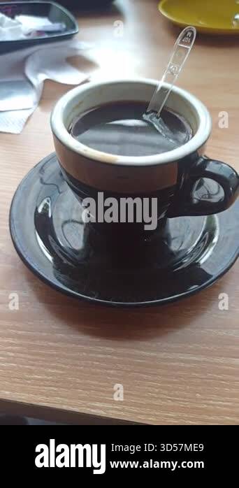 A steaming cup of black Americano coffee, rich and bold, served in a ...
