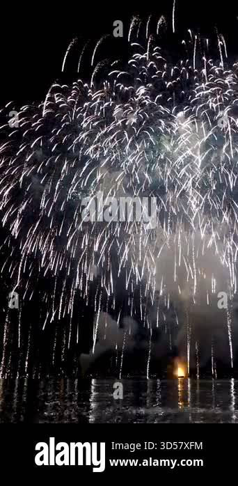 Bright fireworks explode in colorful displays above the calm water ...
