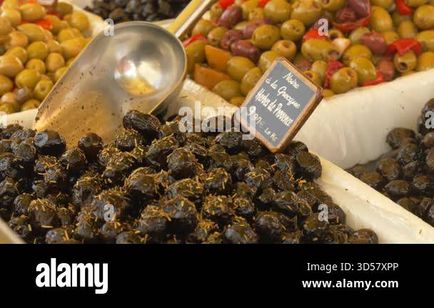 Rustic display of green and dark olives in sunlight at a French market ...