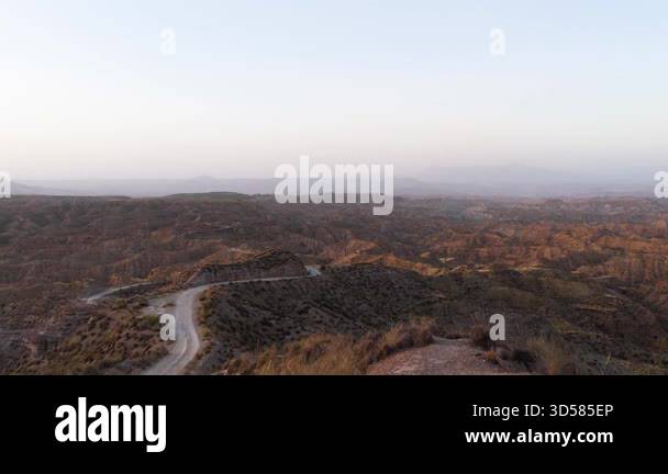 Lone woman standing on a cliff edge overlooking a vast, arid canyon ...
