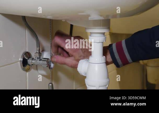 Professional plumber hands turning a chrome shut off valve under a ...