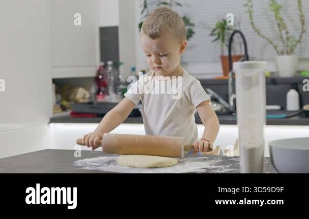 Cute toddler with flour on his face learning to cook by rolling out ...