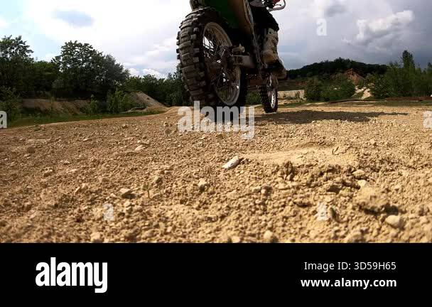 Motorcycle rider speeds across dirt track, creating a cloud of dust ...