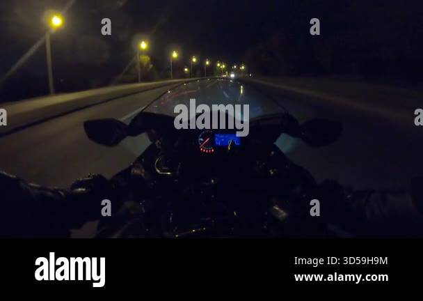 Biker riding a powerful motorcycle through a vibrant city at night ...