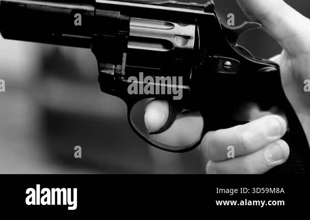 Close-up of a pistol in a hand pulling the trigger and firing a shot ...