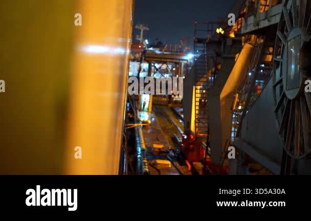 Wet ship deck gleams under floodlights while rain falls. Water flows ...