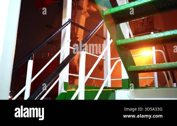 Wet steel ladder glistens under dim light as raindrops slide down steps ...