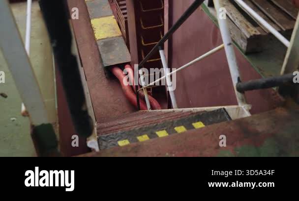 Old metal steps lead to vessel ship engine bay with red pipes. Going ...