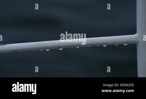 Raindrops hang on white metal railing of sailing vessel closeup. Water ...