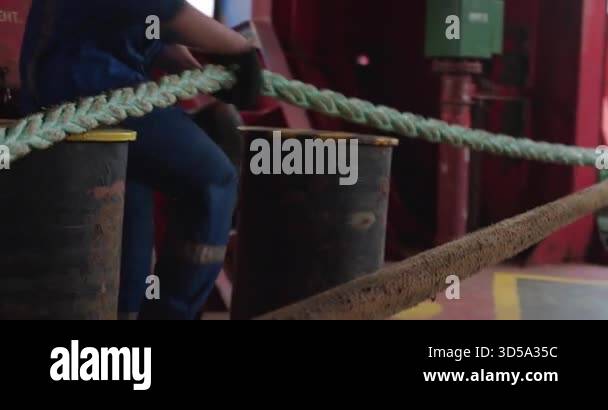 Seasoned sailor pulls thick rope along deck arms tense with strength ...