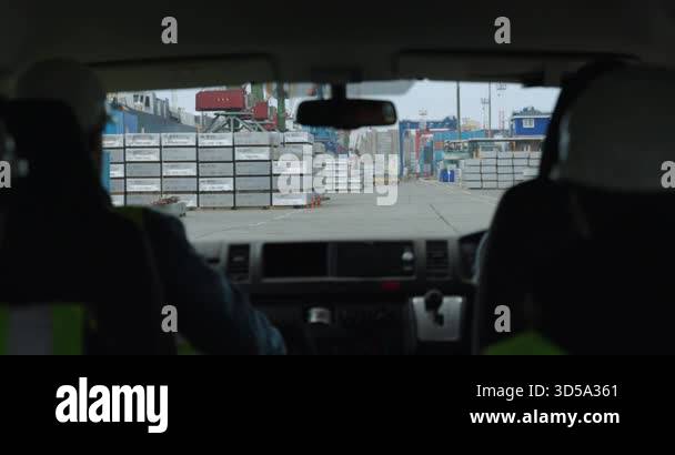 Silent male figures sit in car watching stacked containers ahead ...