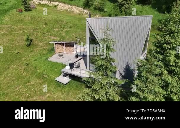 Aerial view of a modern triangular A-frame cabin surrounded by green ...
