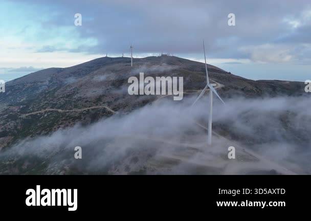 An aerial footage of a mountain top wind farm with spinning wind ...