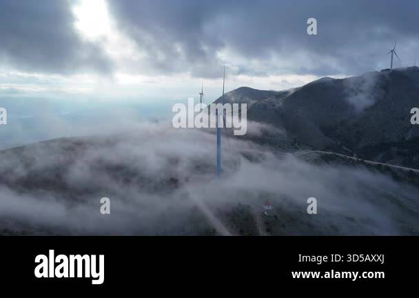 Aerial view of wind turbines on a misty, cloudy mountain top wind farm ...