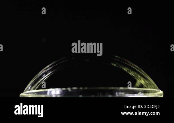 A soap bubble displays vibrant color reflections against a dark ...