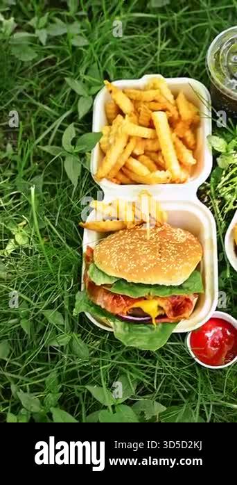 Street food picnic with burgers and fries on grass. Close-up photo of ...