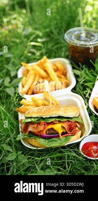 Outdoor picnic with burgers fries and soda on grass. Tasty burgers ...