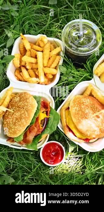 Fast food picnic with burgers fries and cola on grass. Tasty fast food ...