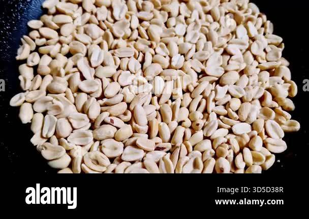 Macro top-down view of shelled and split peanuts filling a black ...