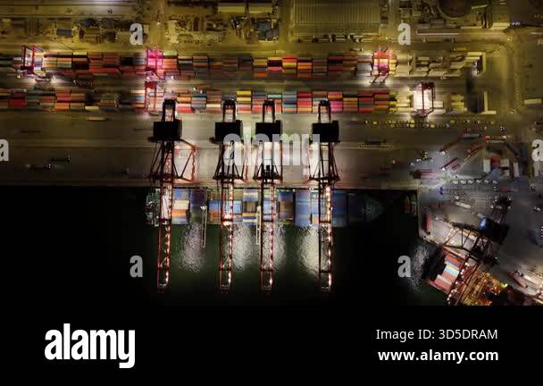 Top down aerial view of a bustling container terminal at night, showing ...