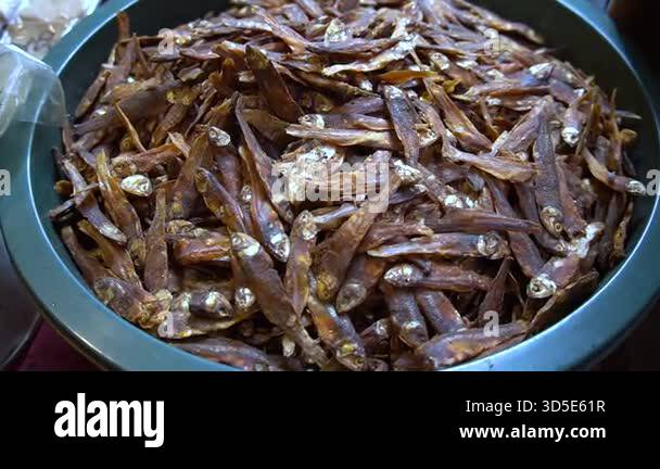 Close up of a bowl filled with many tiny, dried brown fish, tightly ...