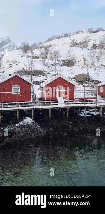 Red wooden rorbu house in fjord in Nusfjord, one of the oldest ...