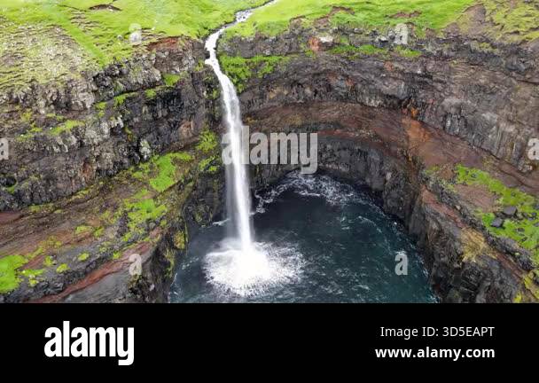 Dramatic Mulafossur waterfall plunging into the ocean with Gasadalur ...