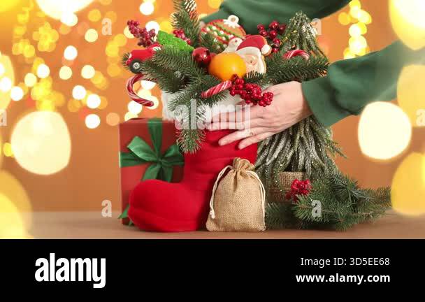 Saint Nicholas day. Woman adjusting red boot with treats and festive ...