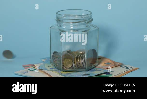 Coins falling into jar on light blue background, closeup. Money savings ...