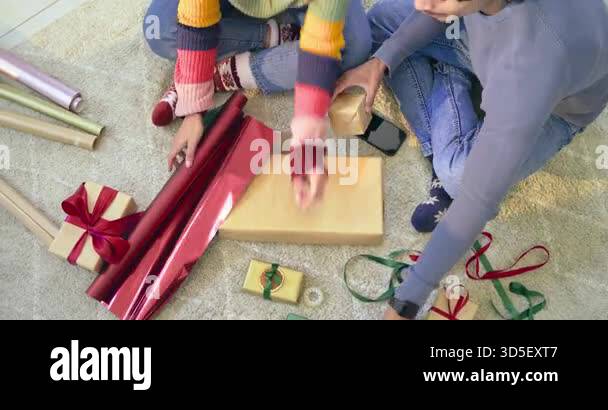 After unwrapping red gift wrap couple is cutting, taping kraft boxes on ...
