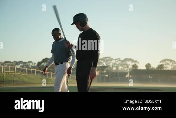 Nodding coach guiding African American player into batting stance at ...