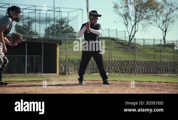 Male batter swinging bat at home plate after pitch arrival, with runner ...