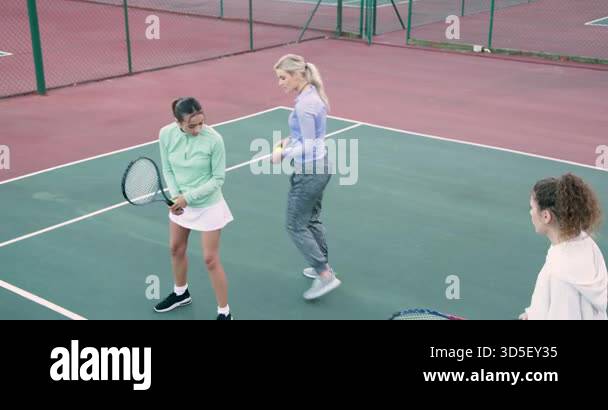 Receiving racket, female coach picking balls, adjusting student grip on ...