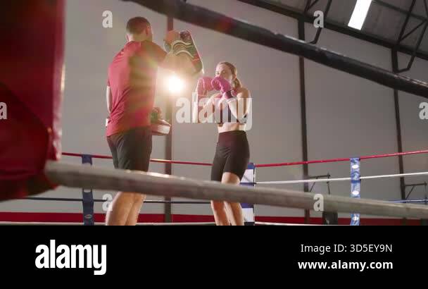 Boxing coach raising mitts, boxer delivering jab and cross into focus ...