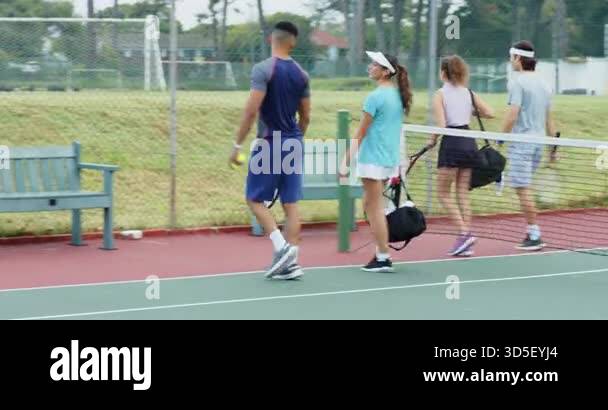 Reaching bench, diverse tennis friends retrieving balls and warming up ...