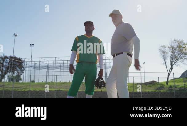Pointing male coach and player adjusting baseball glove on field with ...