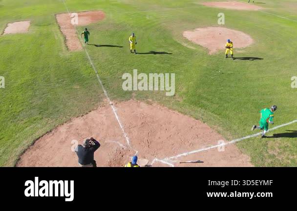 Green-uniformed male runner sliding home on baseball field after swing ...