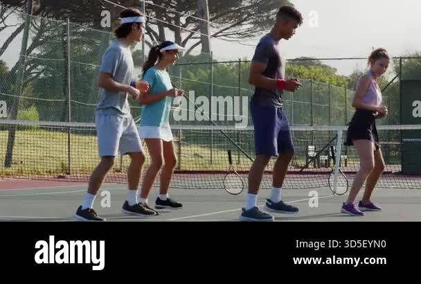 Starting Diverse tennis teammates simulating jump-rope warm-up on ...