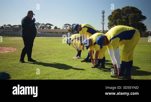 Walking male baseball coach and team bending, stretching in outfield ...