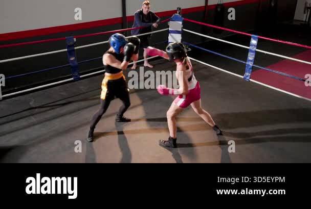 Female boxer in pink retreating into ring corner getting coach glove ...
