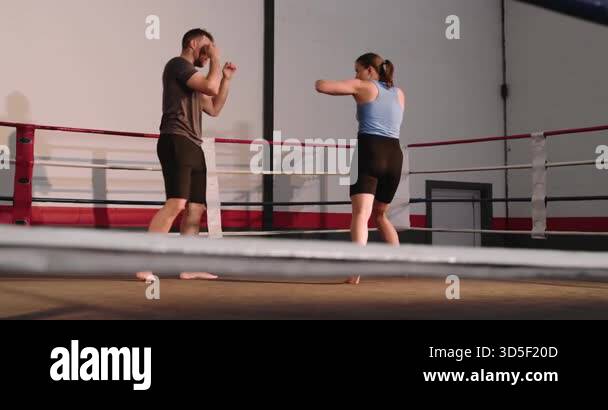 Coach and trainee stepping into boxing ring, performing gloved feint ...