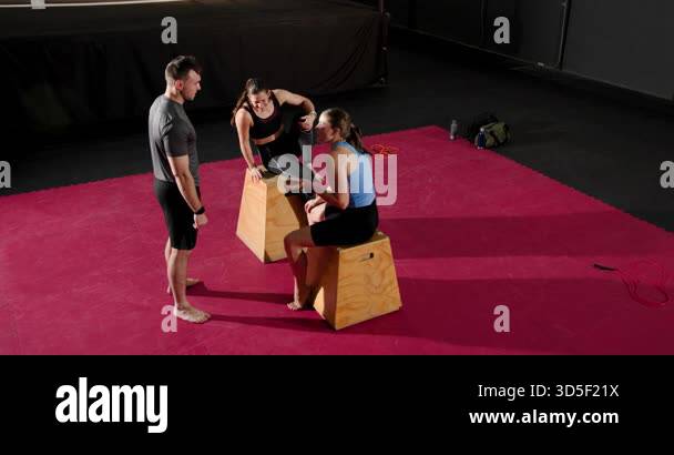 Male instructor gesturing footwork cues while female trainees mimicking ...