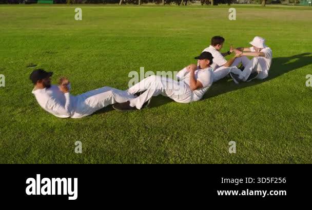 Doing alternating sit-ups and hand claps Diverse male teammates in ...