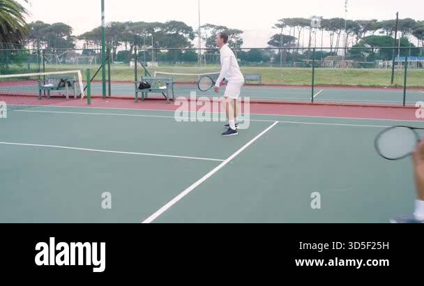 Approaching ball, two male tennis partners volleying ball on outdoor ...