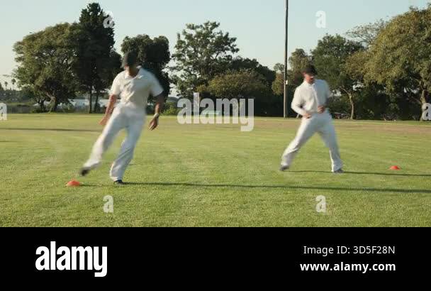 Diverse male cricket teammates running through orange-green cones ...